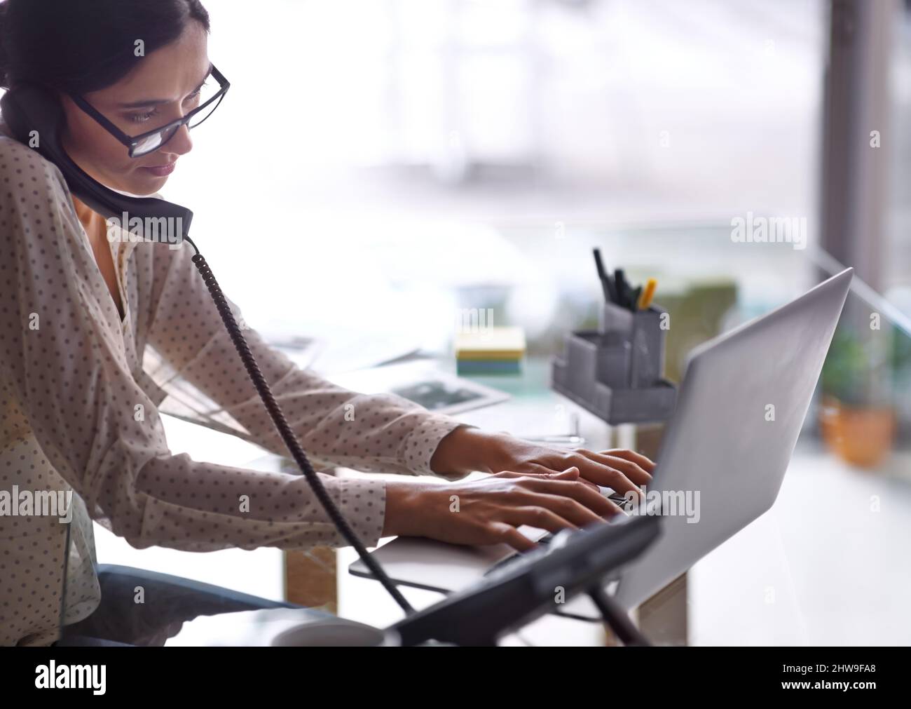 Doing it all at once. Shot of a beautiful young businesswoman working ...