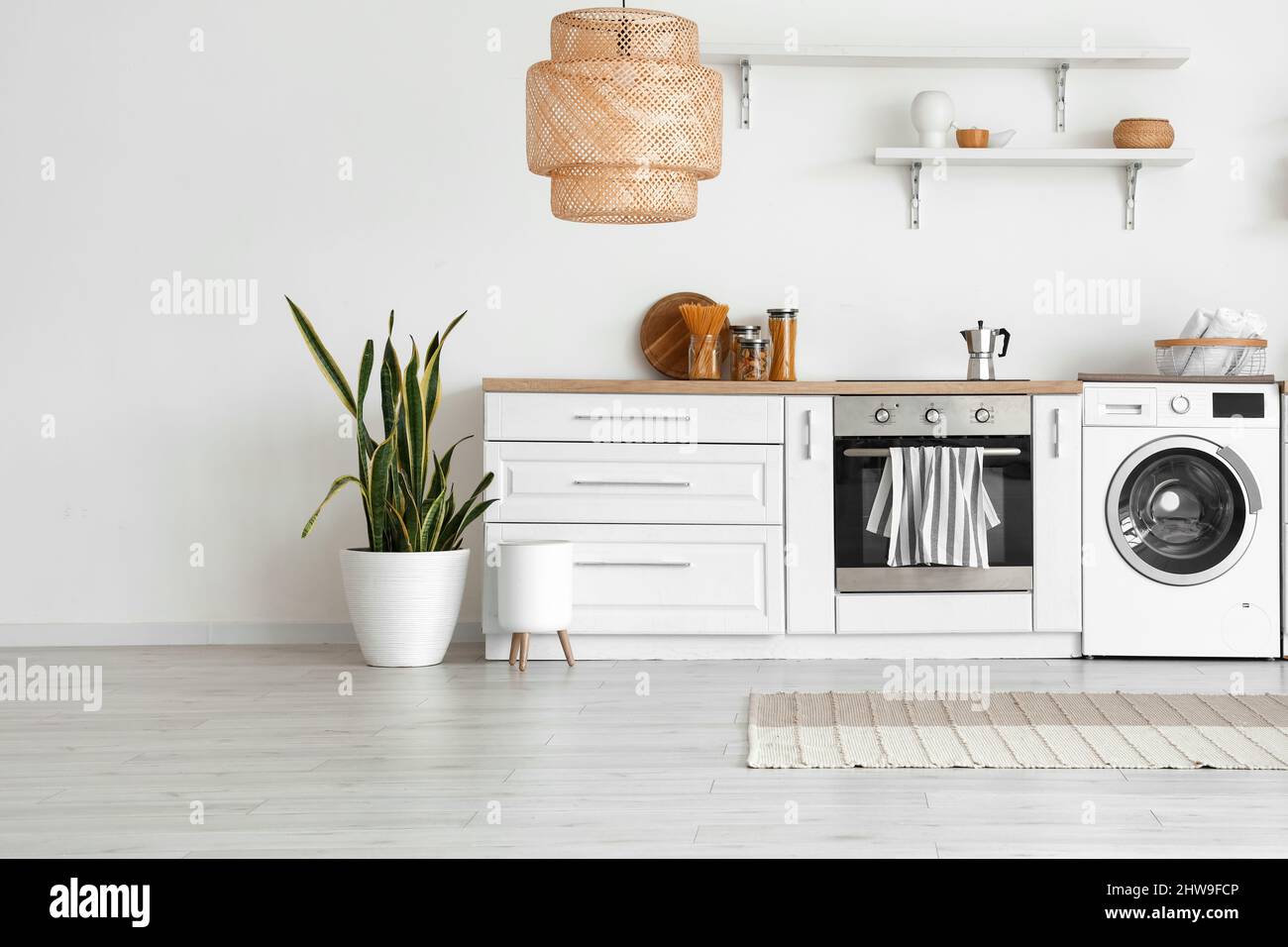 Interior of light kitchen with washing machine, oven and white counter ...
