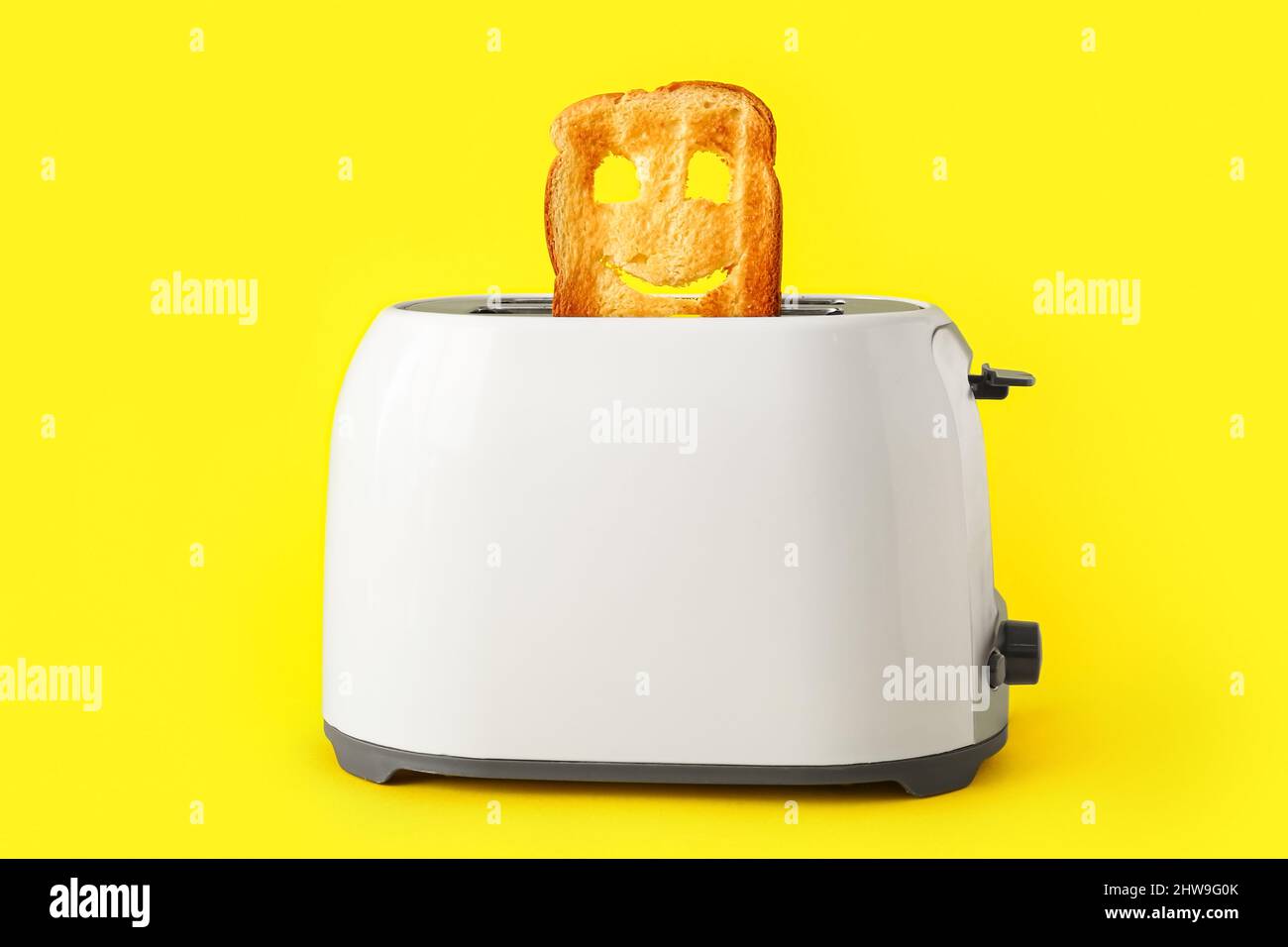 Funny slice of bread in toaster on yellow background Stock Photo - Alamy