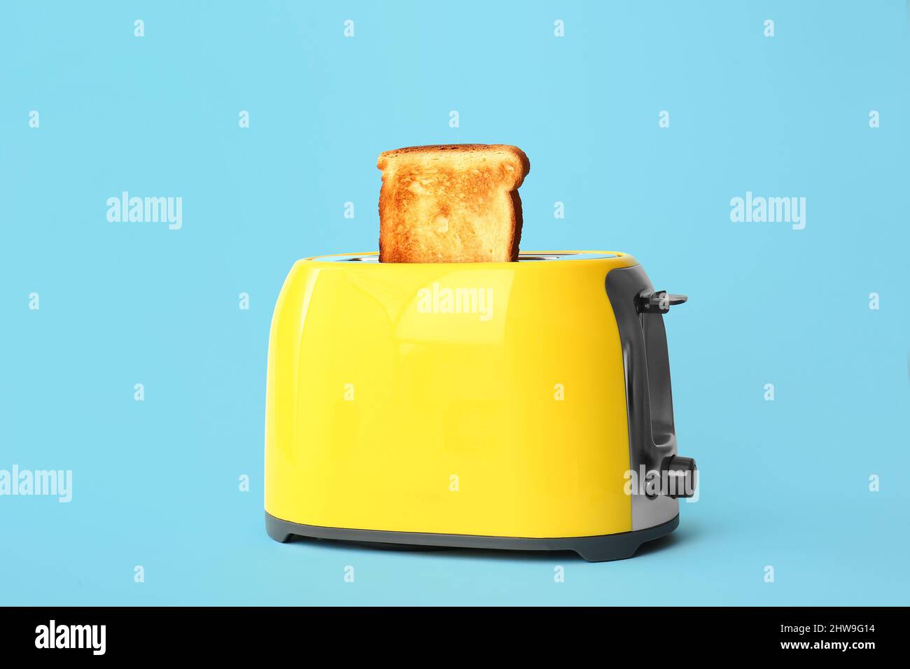 Modern toaster with bread slice on blue background Stock Photo - Alamy