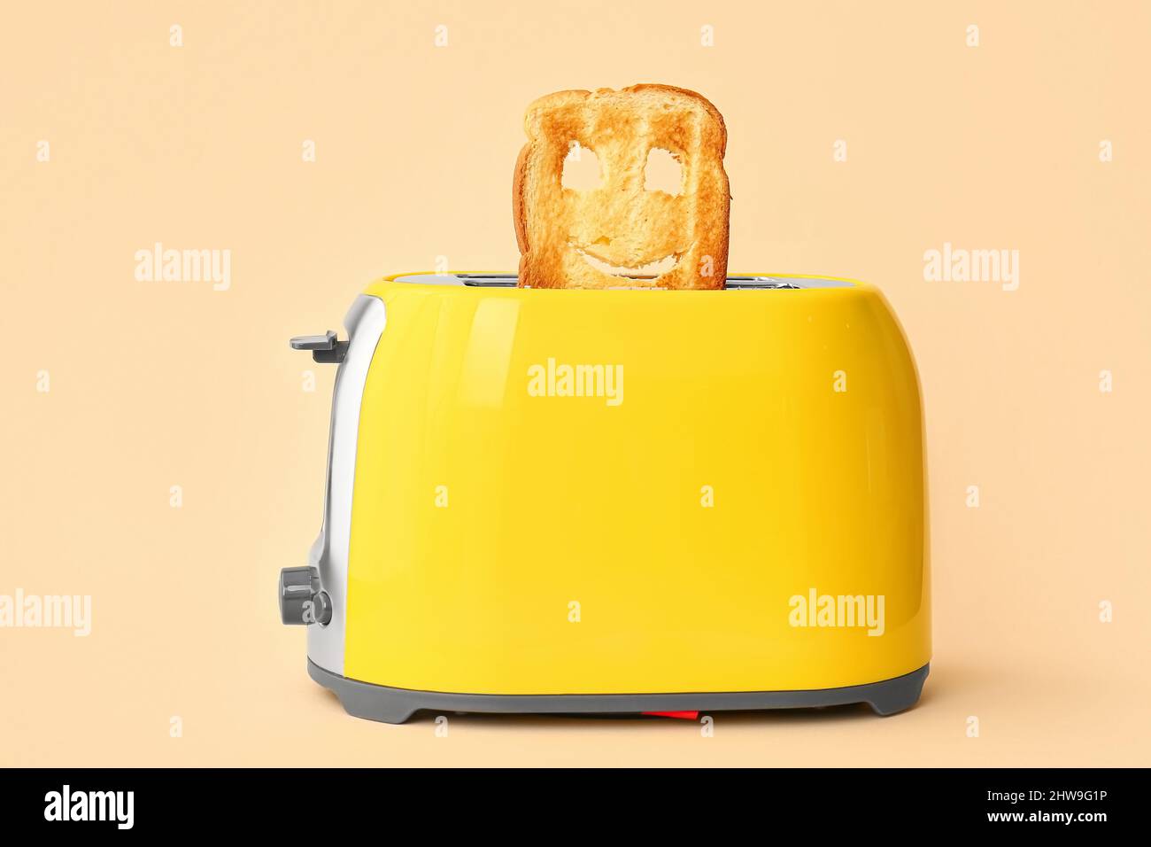 Funny slice of bread in toaster on beige background Stock Photo - Alamy