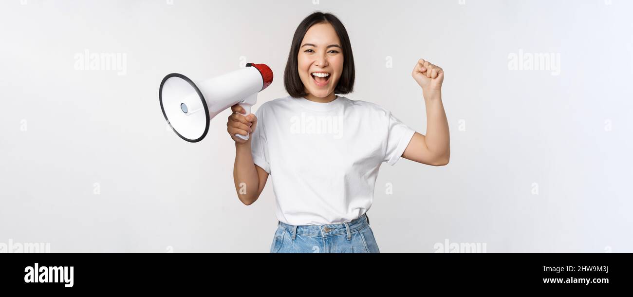 Happy asian woman shouting at megaphone, making announcement ...