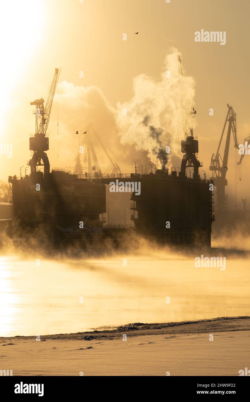 Cranes of shipyard in frosty winter day, steam over river, smooth ...