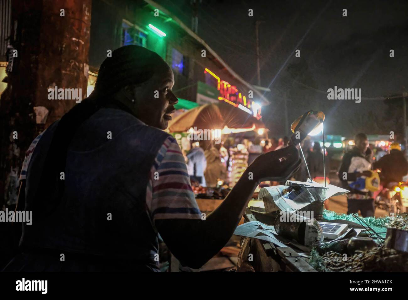 A street vendor using a solar lamp while providing services to her ...