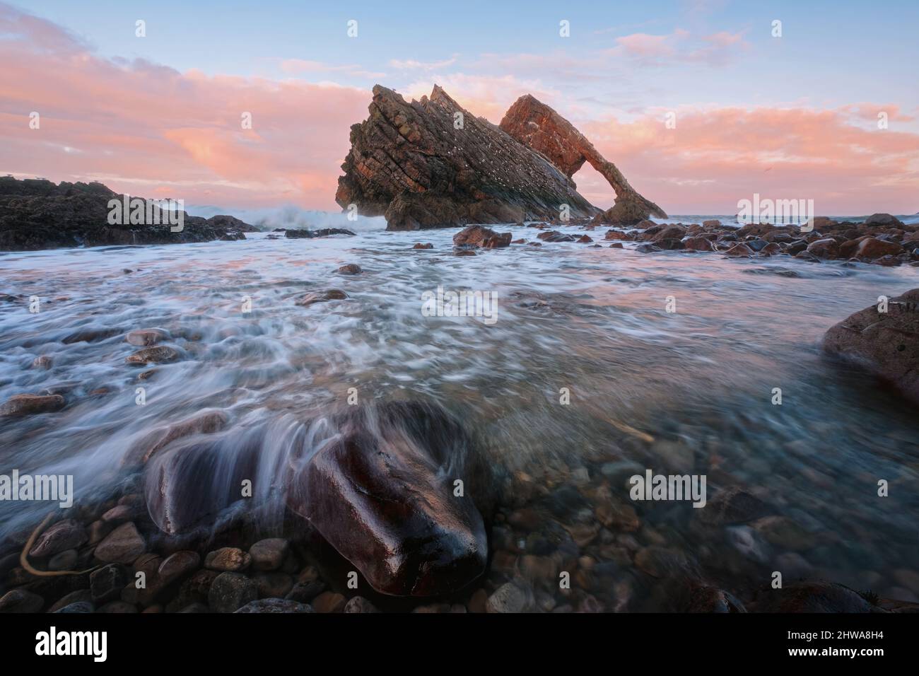 Landscape of natural sea arch and stones in the foreground covered with ...