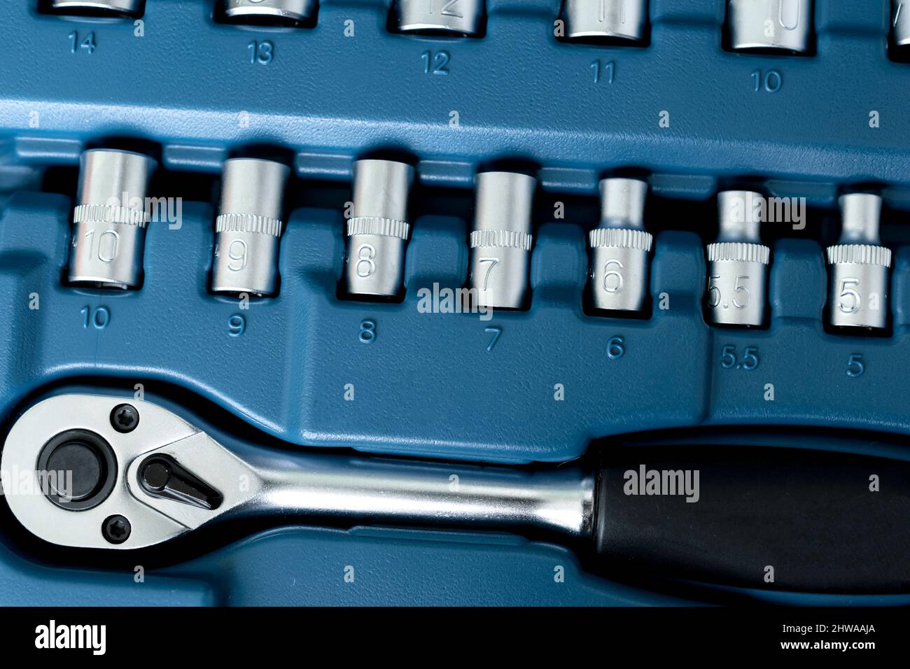 Top view of ratchet wrench and some stainless steel hex sockets on blue ...