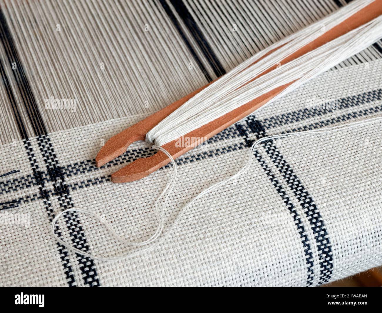 Hand loom with black and white striped woven cloth and wooden shuttle ...