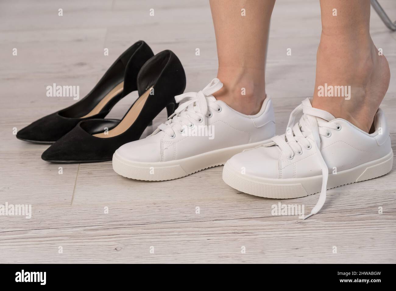Close-up business woman takes off her shoes puts on white leather ...