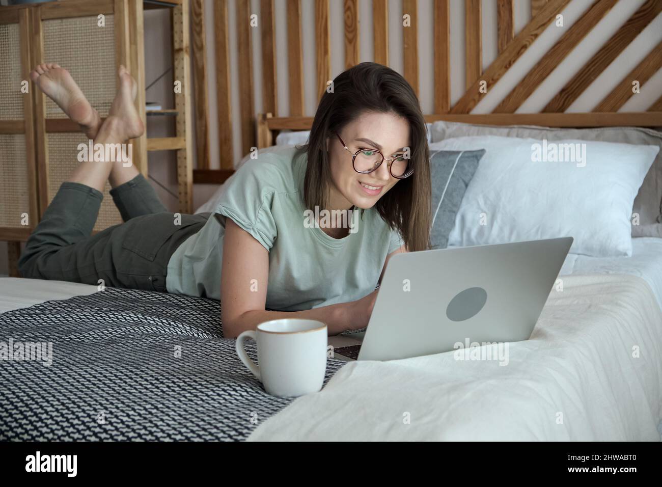 Young happy woman using laptop, typing, smiling and looking at screen ...