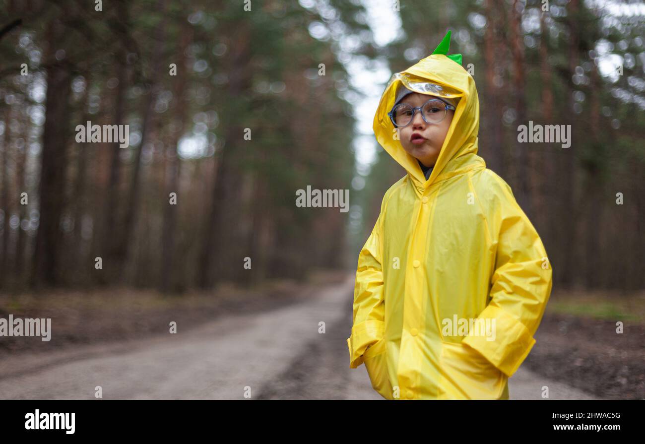 Child in a yellow raincoat walks in the forest and has fun Stock Photo ...