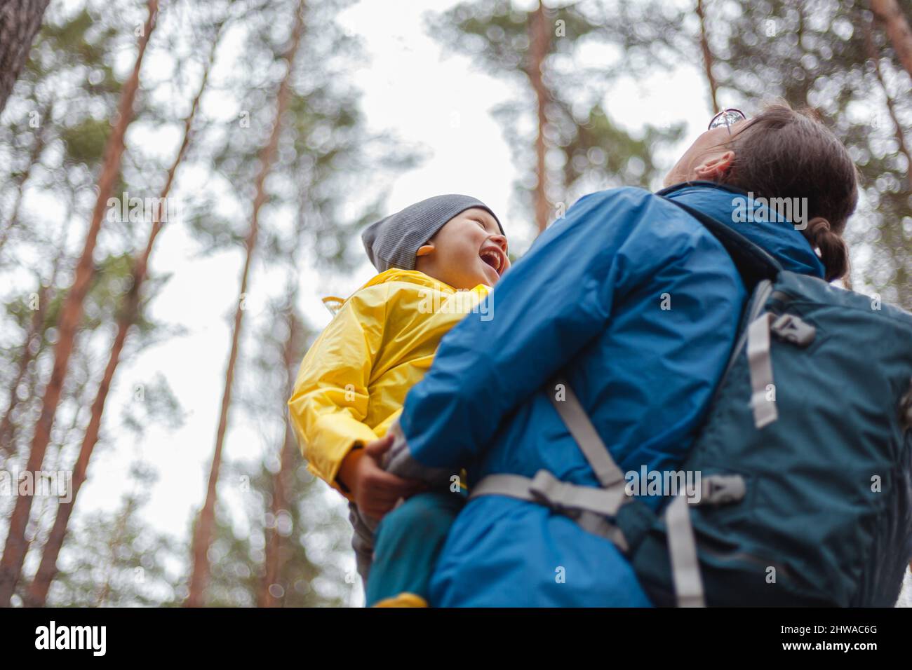 Happy family Mom and child walk in the forest after rain in raincoats ...