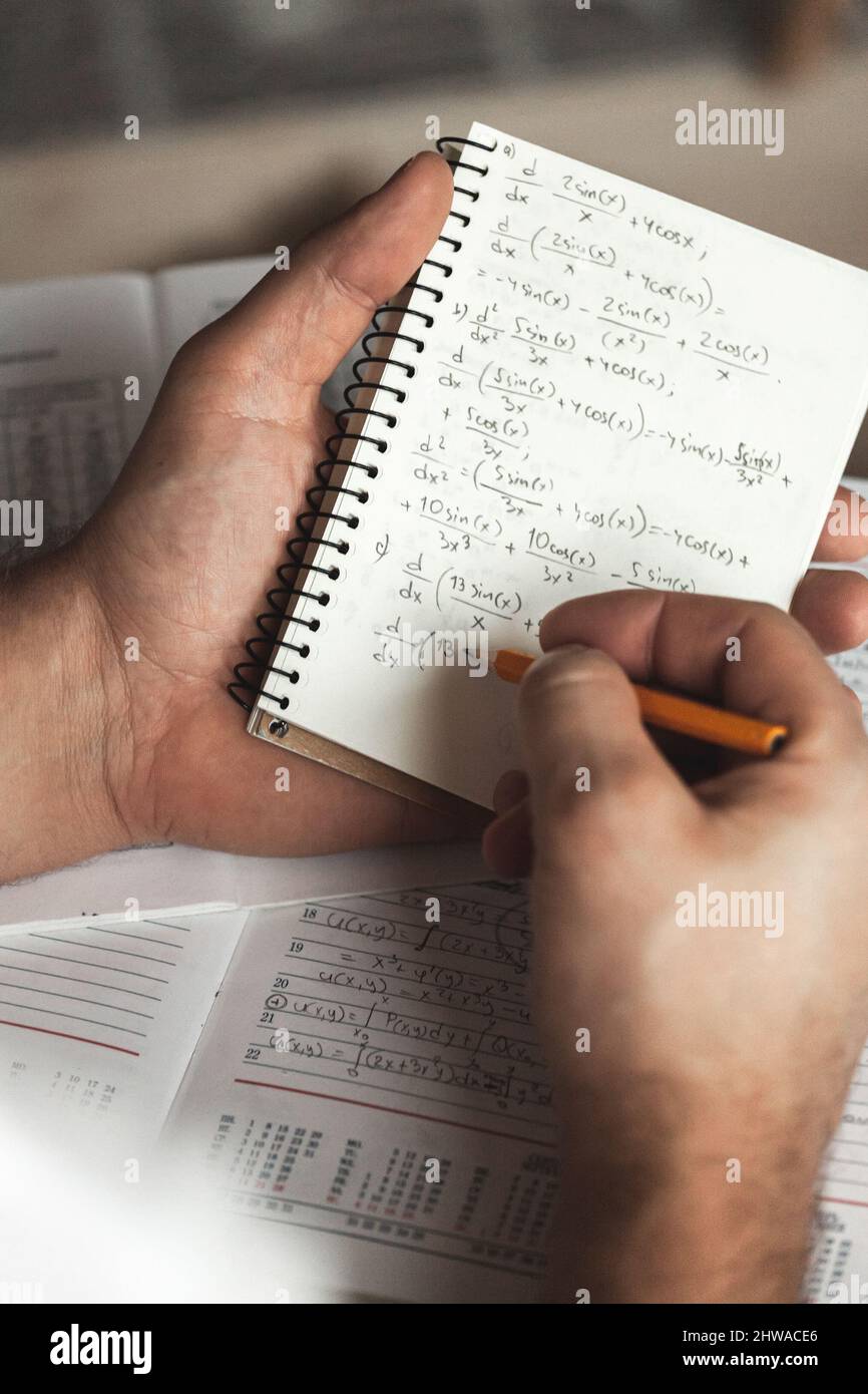 Math formulas are written in pencil in a notebook holding man in Stock ...