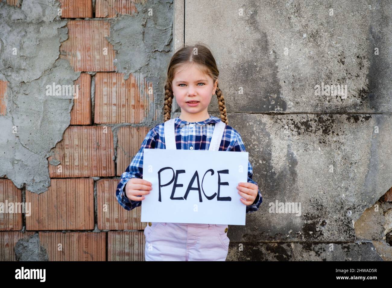 Child girl holding a poster with written PEACE in support of peace ...