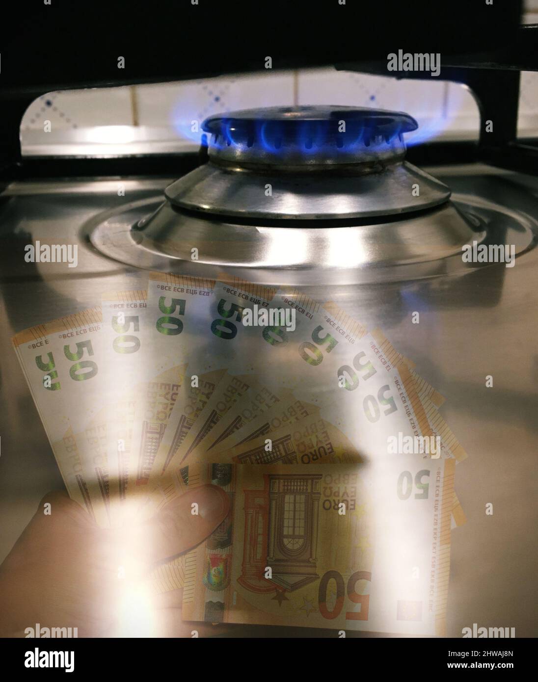 Hand holding euro banknotes with a gas flame as background, concept of ...