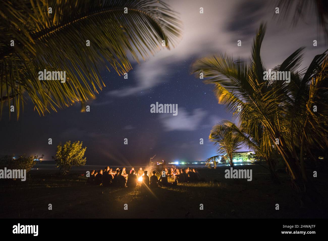 Beautiful shot of a group of people sitting around fire on a tropical beach at night Stock Photo ...