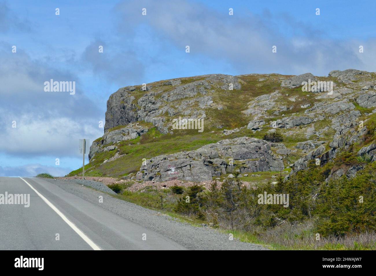 Bedrock cliff against blue sky along Newfoundland highway during Spring ...