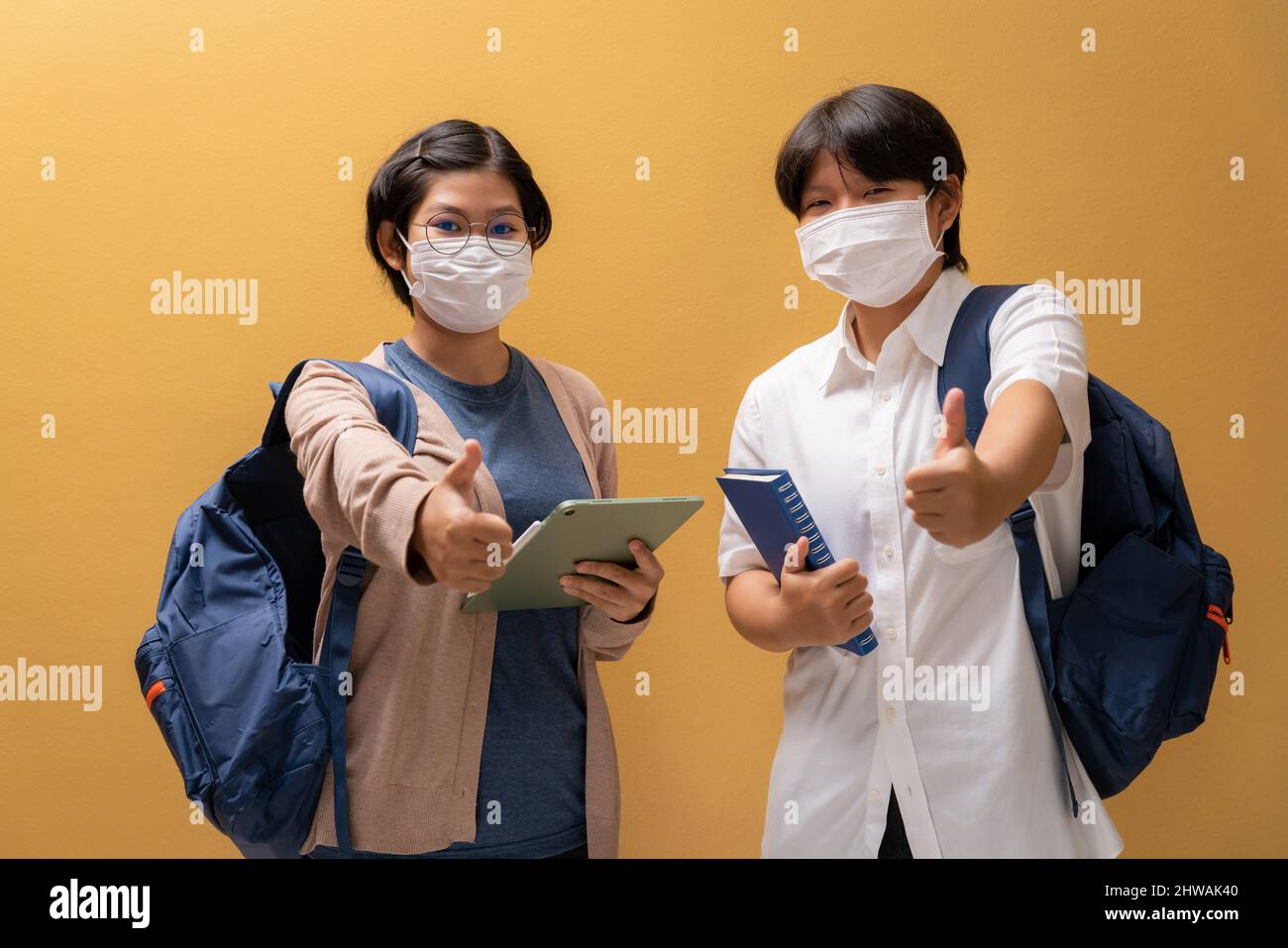 Two girls giving wear a protective mask with thumb up and learning ...