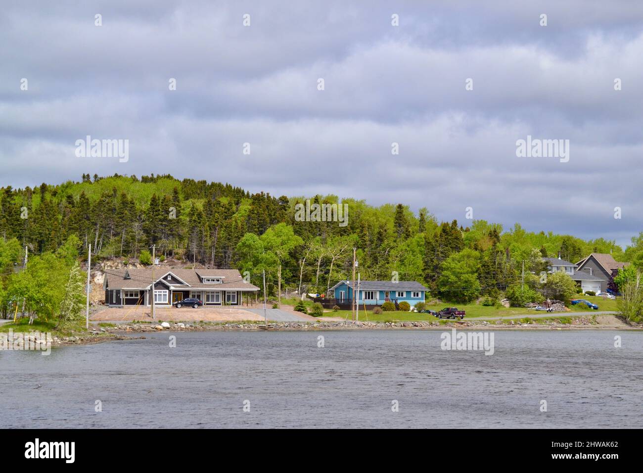 Homes and hilly landscape along bay in Newfoundland during Spring Stock ...