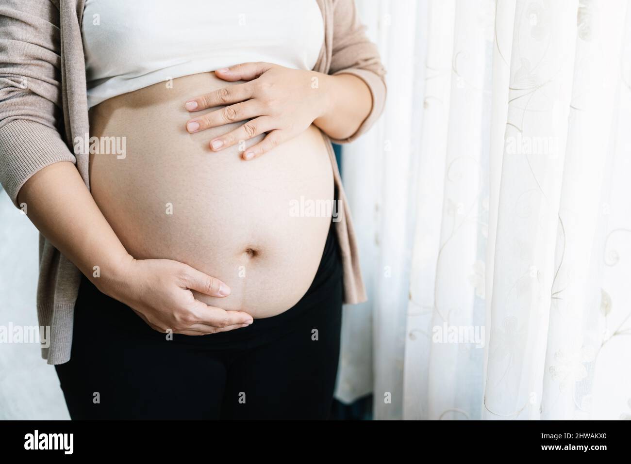 Pregnant woman with big belly at window. pregnancy, motherhood, people ...