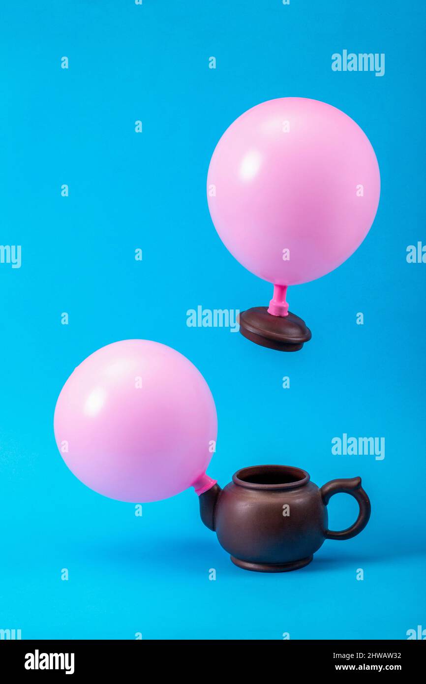 Two pink balloons on a teapot on a blue background Stock Photo - Alamy