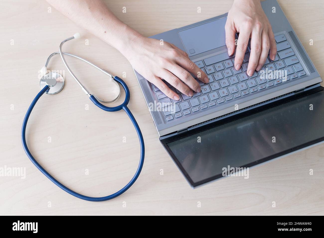 Top view of hands on the keyboard. Woman doctor at the desk typing on a ...