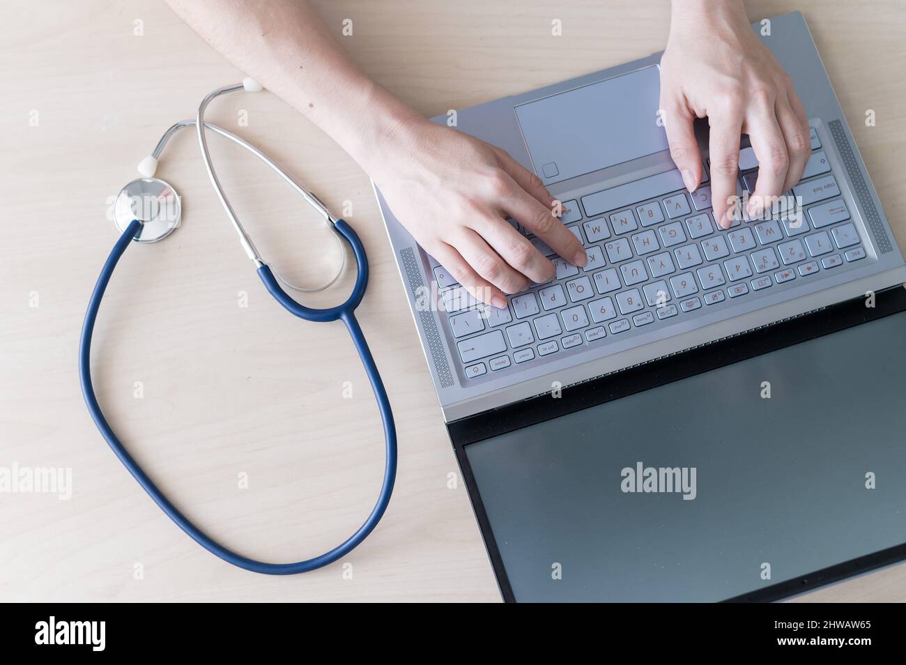 Top view of hands on the keyboard. Woman doctor at the desk typing on a ...