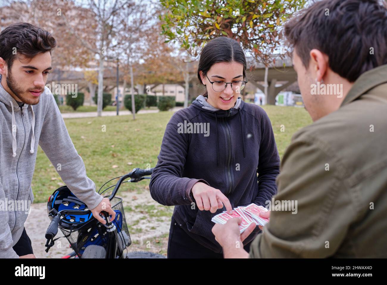 Woman picking a card from the hand of a street magician Stock Photo - Alamy