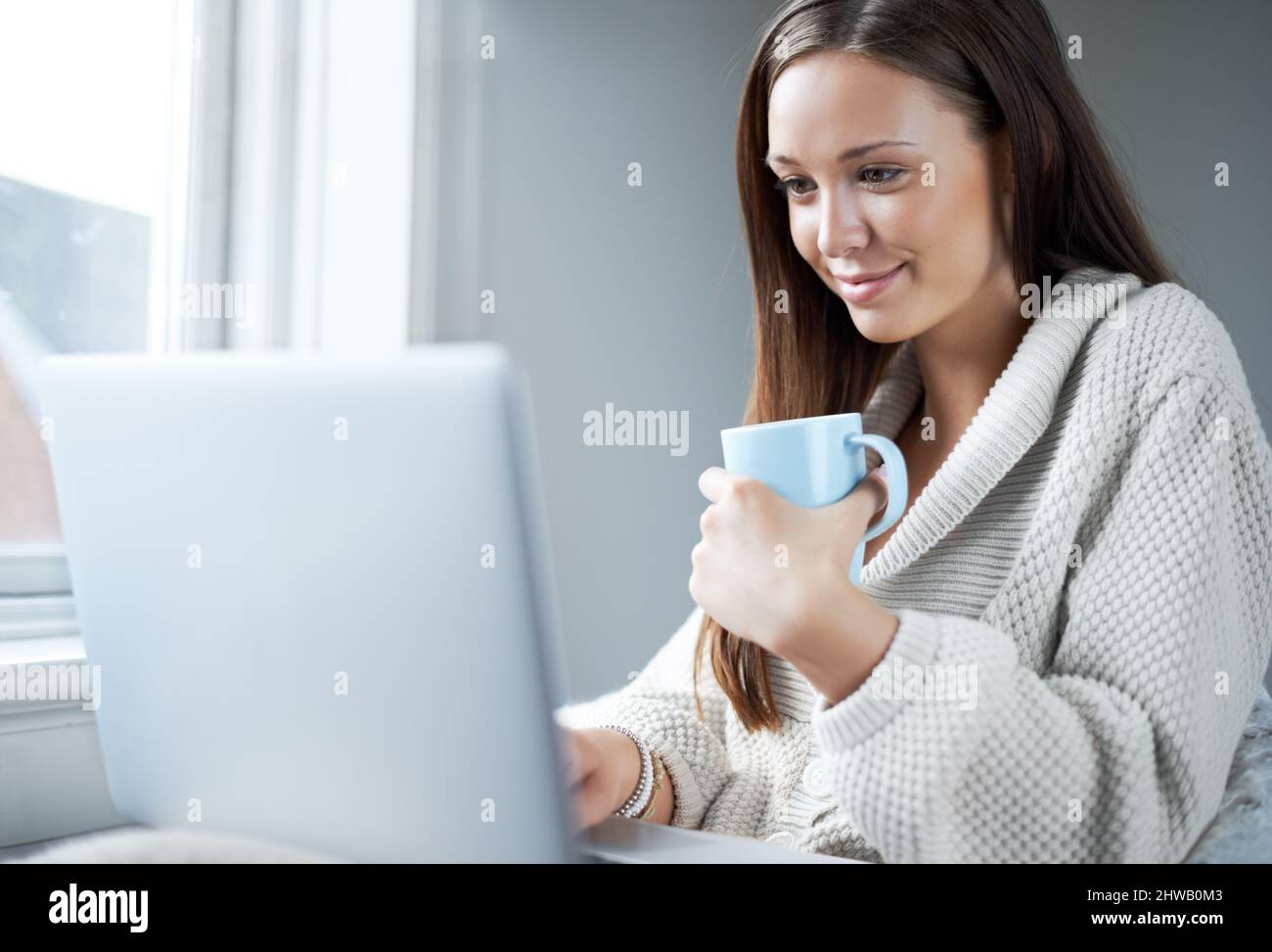 Ive got mail.... Attractive young brunette sipping coffee while sitting ...