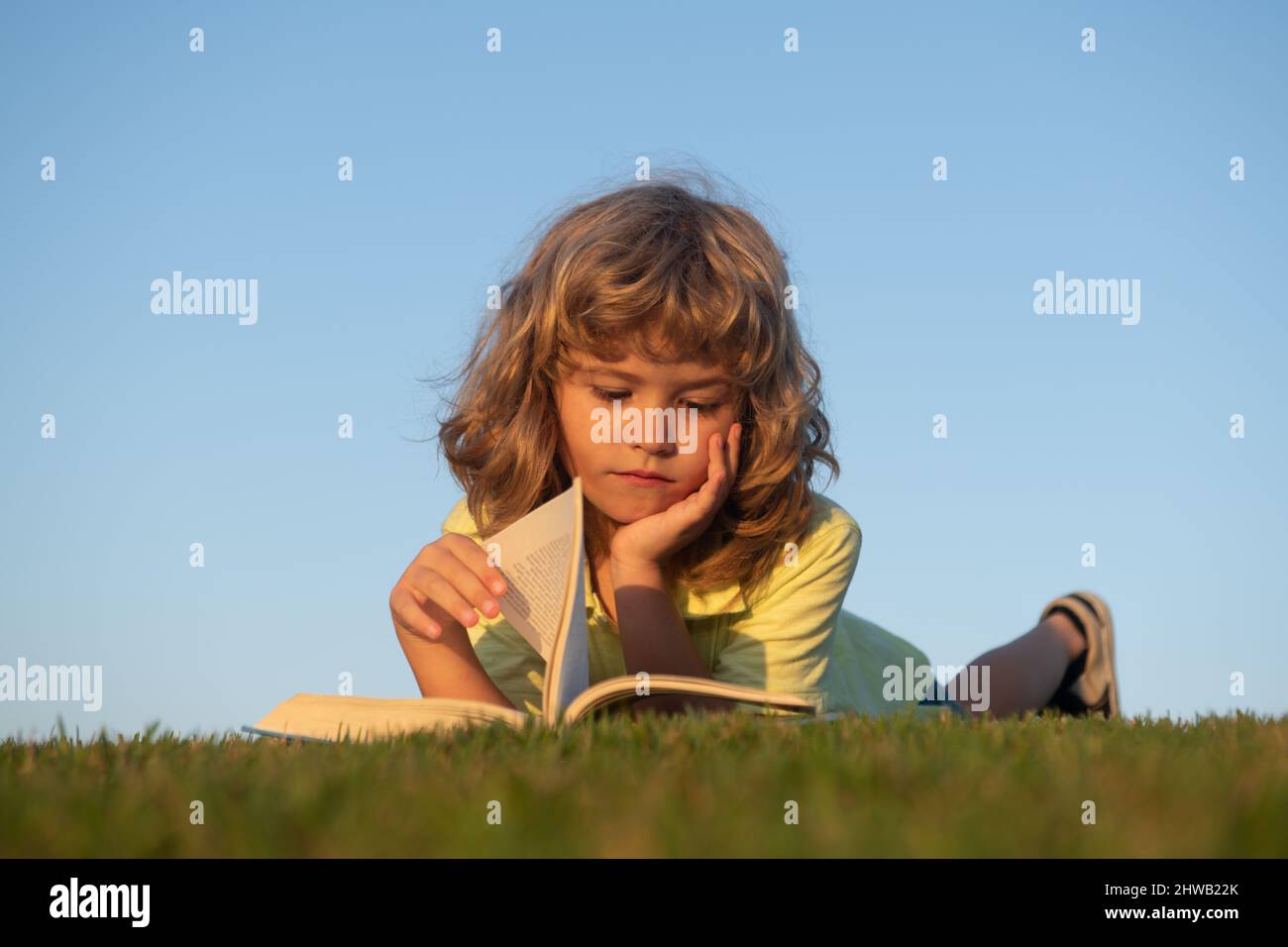 Smart kid boy reading book in park outdoors Stock Photo - Alamy