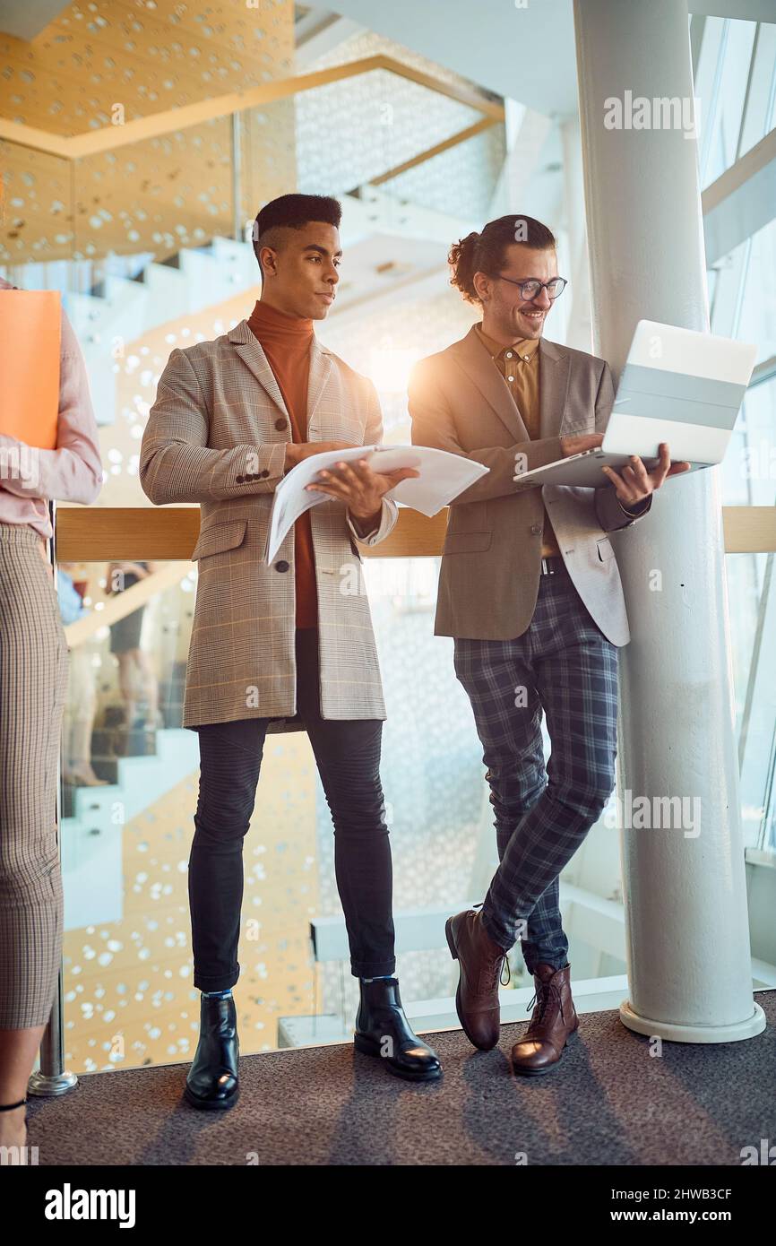 Two young businessmen are standing in a pleasant atmosphere in the ...