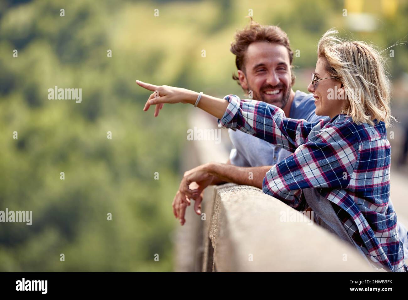 Young smiling couple sharing a beautiful moment together on a bridge ...