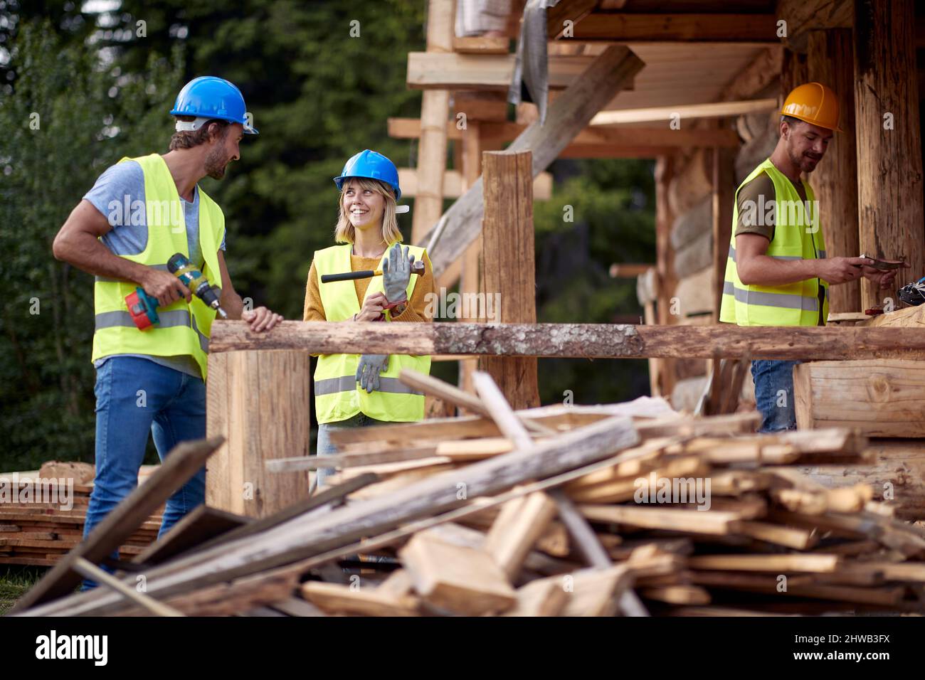Young cheerful construction workers working on wooden house construct ...