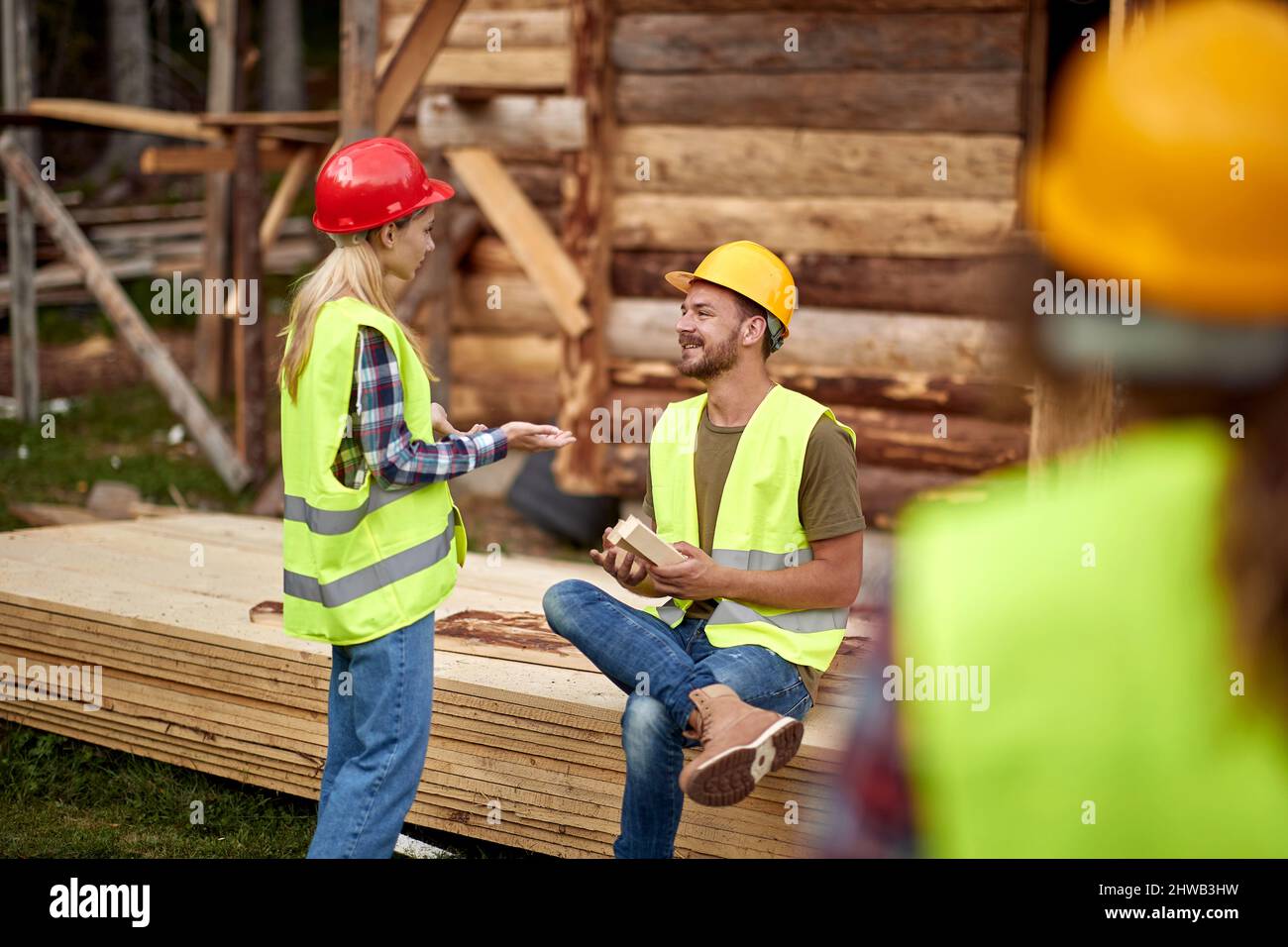 Two young construction workers chatting in front of wooden house ...