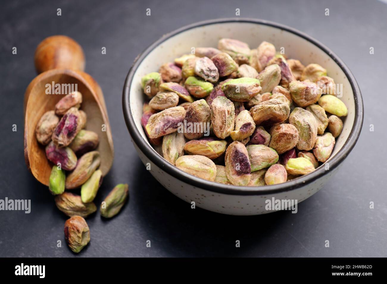 Peeled pistachio nuts in a bowl over black background. Baked pistachios ...
