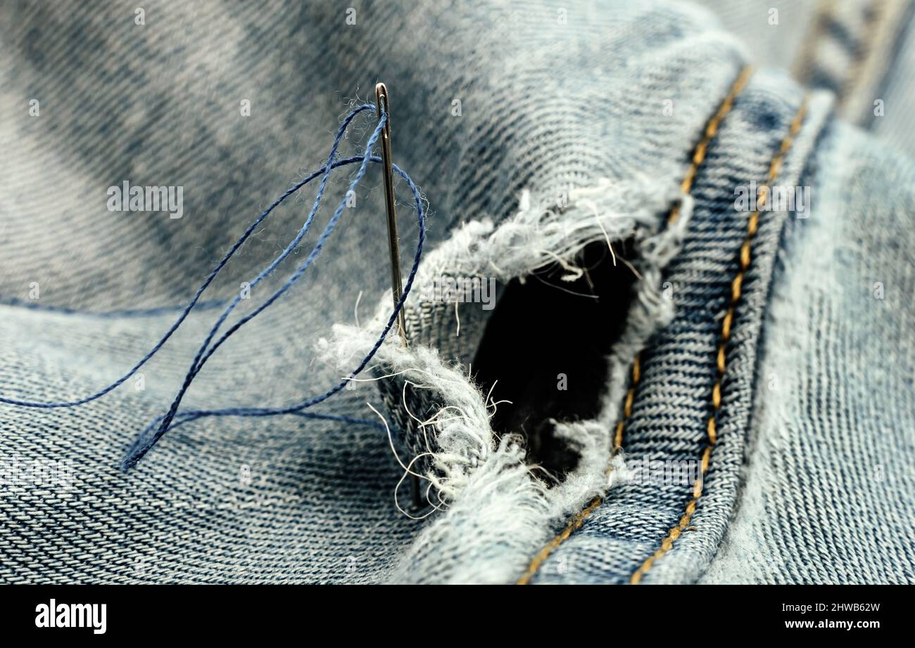 Hole in jeans. Needle with thread for darning jeans. Tools for work ...