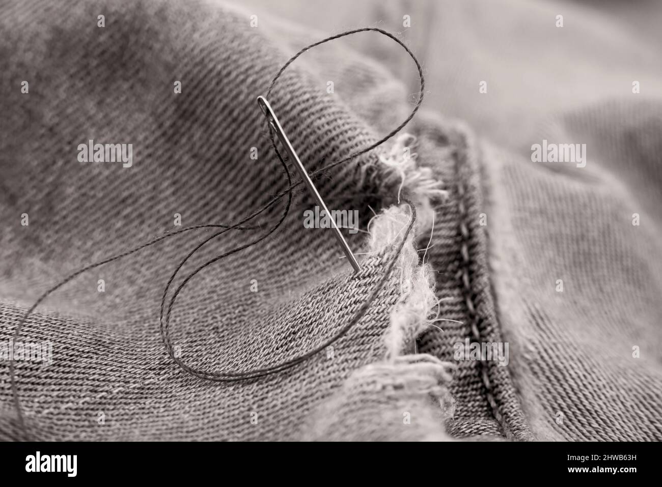 Hole in jeans. Needle with thread for darning jeans. Tools for work ...