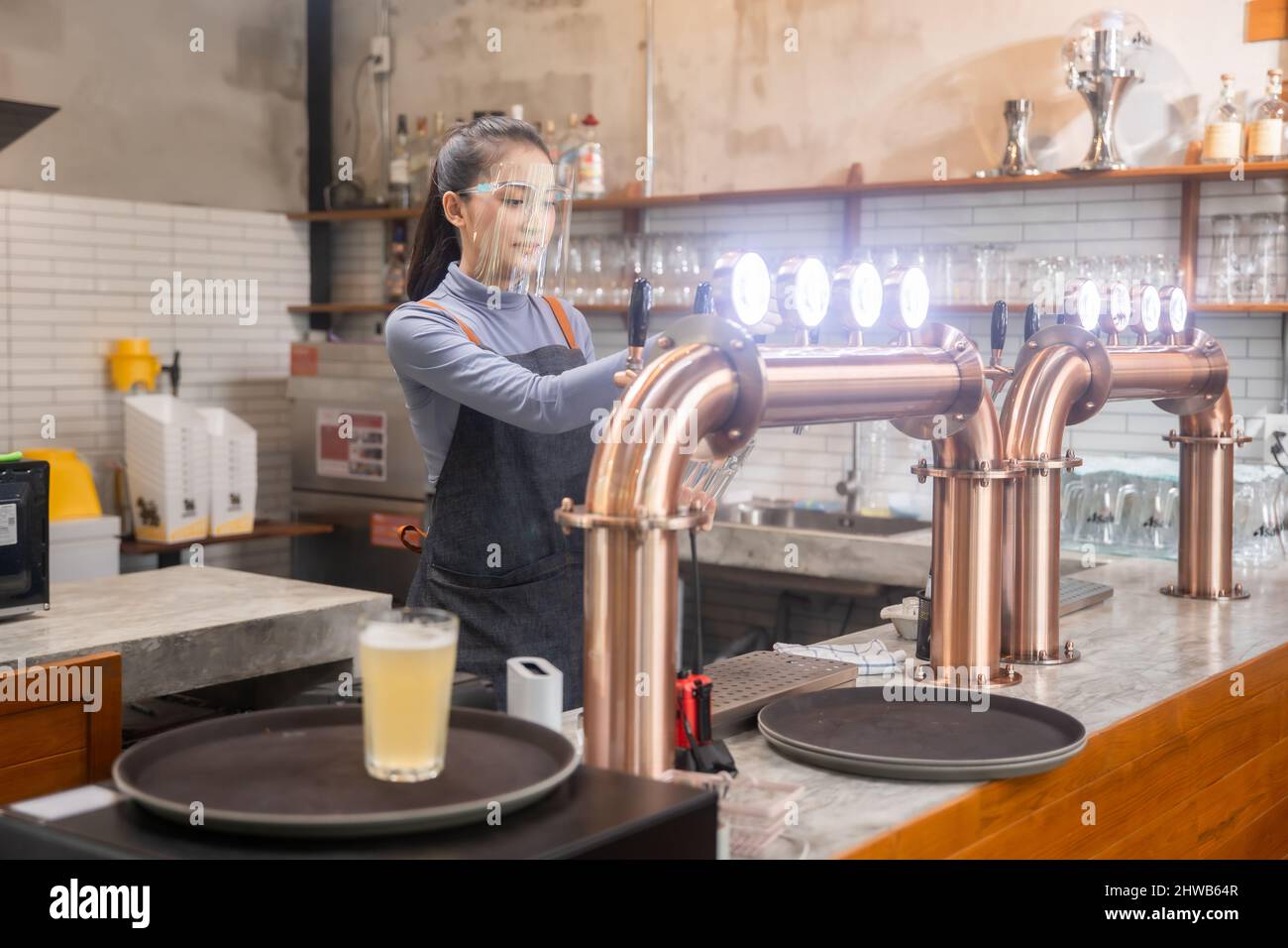 Portrait of Asian bartender girl hand at beer tap pouring , waitress or ...