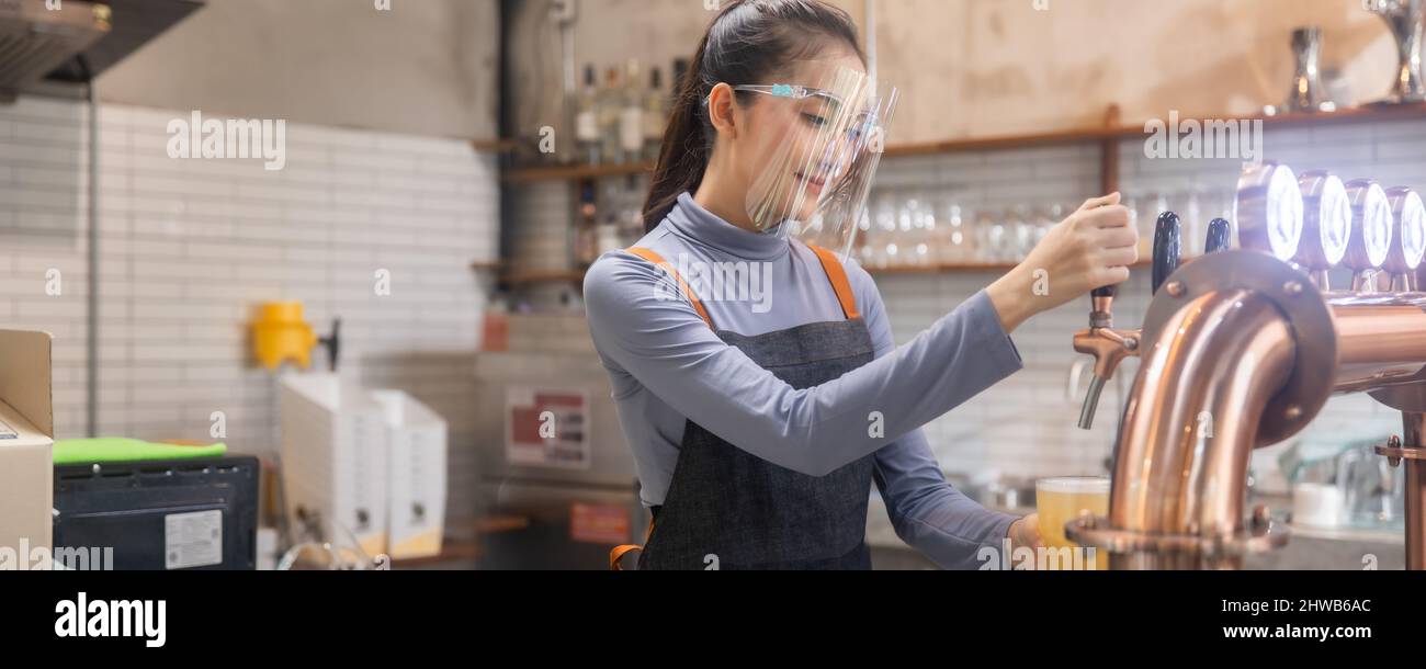 Portrait of Asian bartender girl hand at beer tap pouring , waitress or ...
