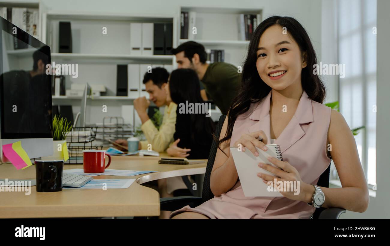 portrait confidential business Asian woman sitting and smile in office with team colleague ...