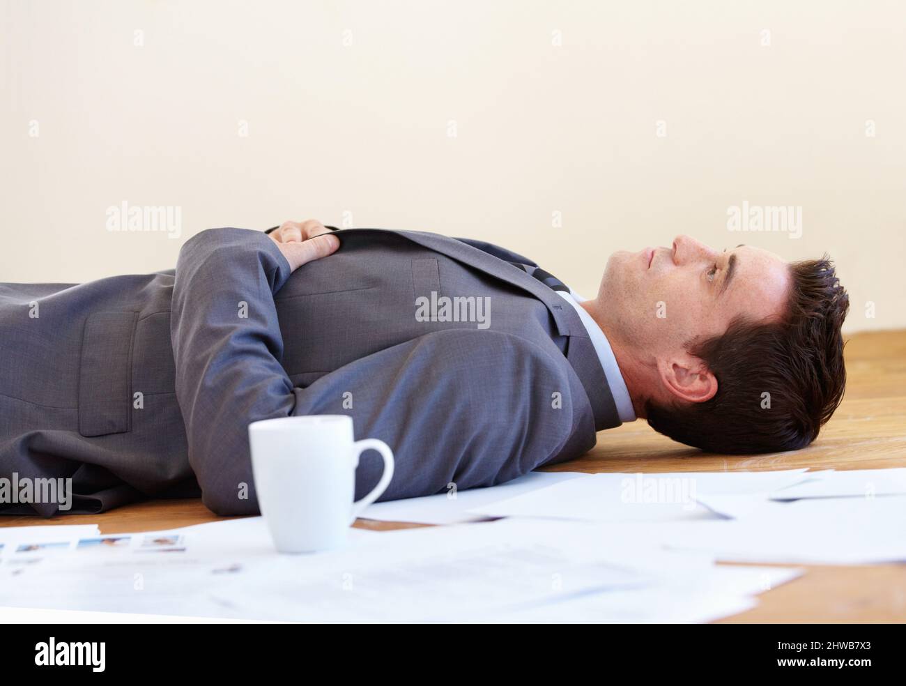 Work really takes its toll. A handsome young businessman lying on the ...