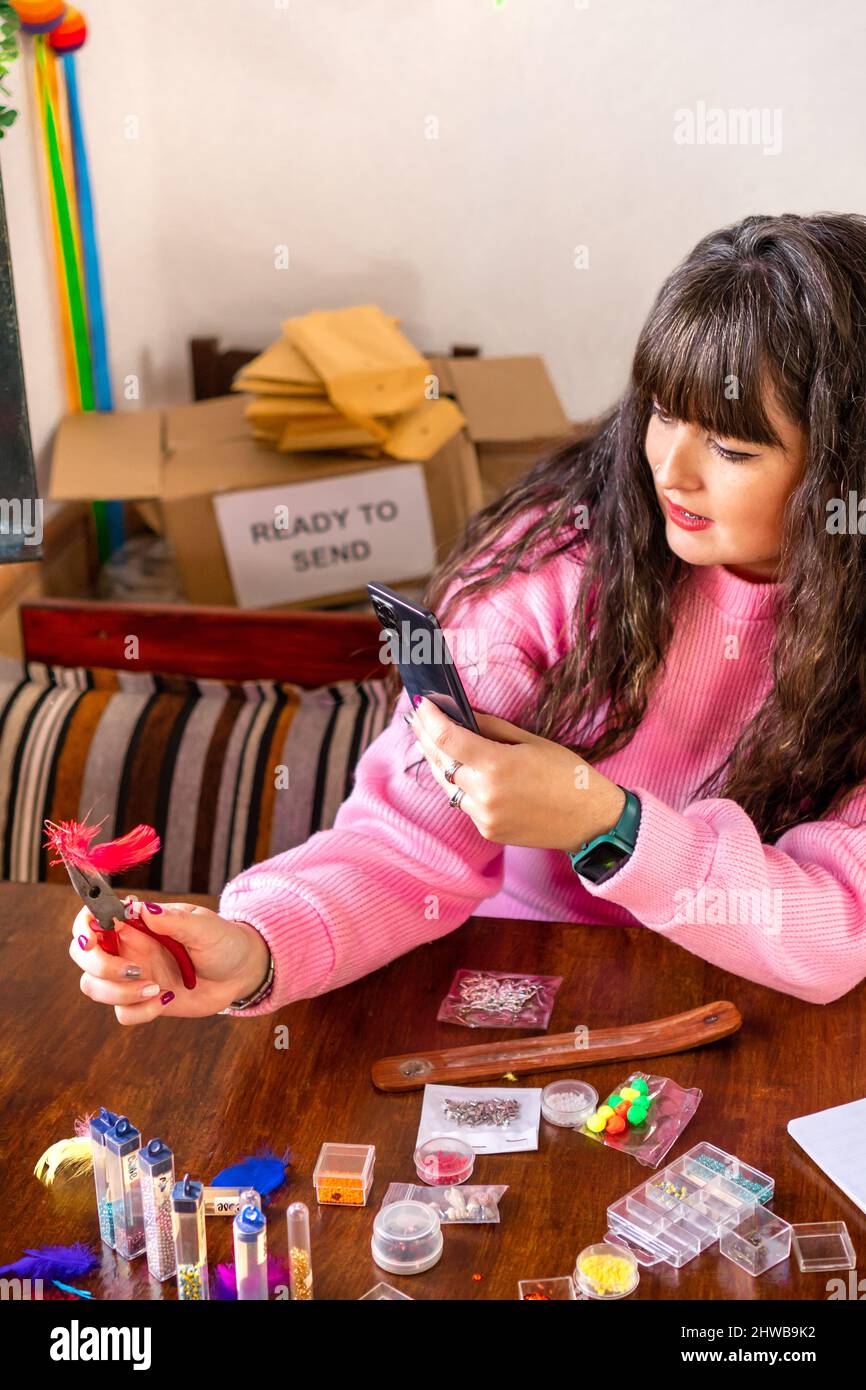 Artisan woman making handmade accessory and taking photo for media ...