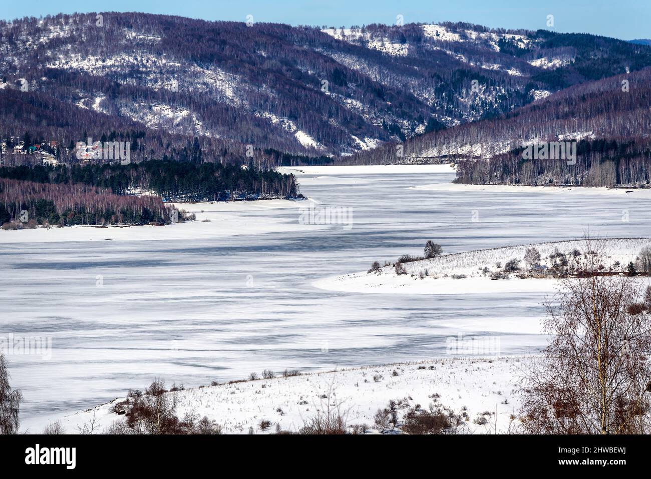 Winter landscape by the frozen lake with hills in the background ...
