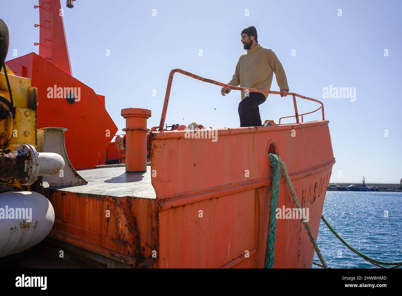 Young hard-working man with a beard and a sailor sweater does chores on ...