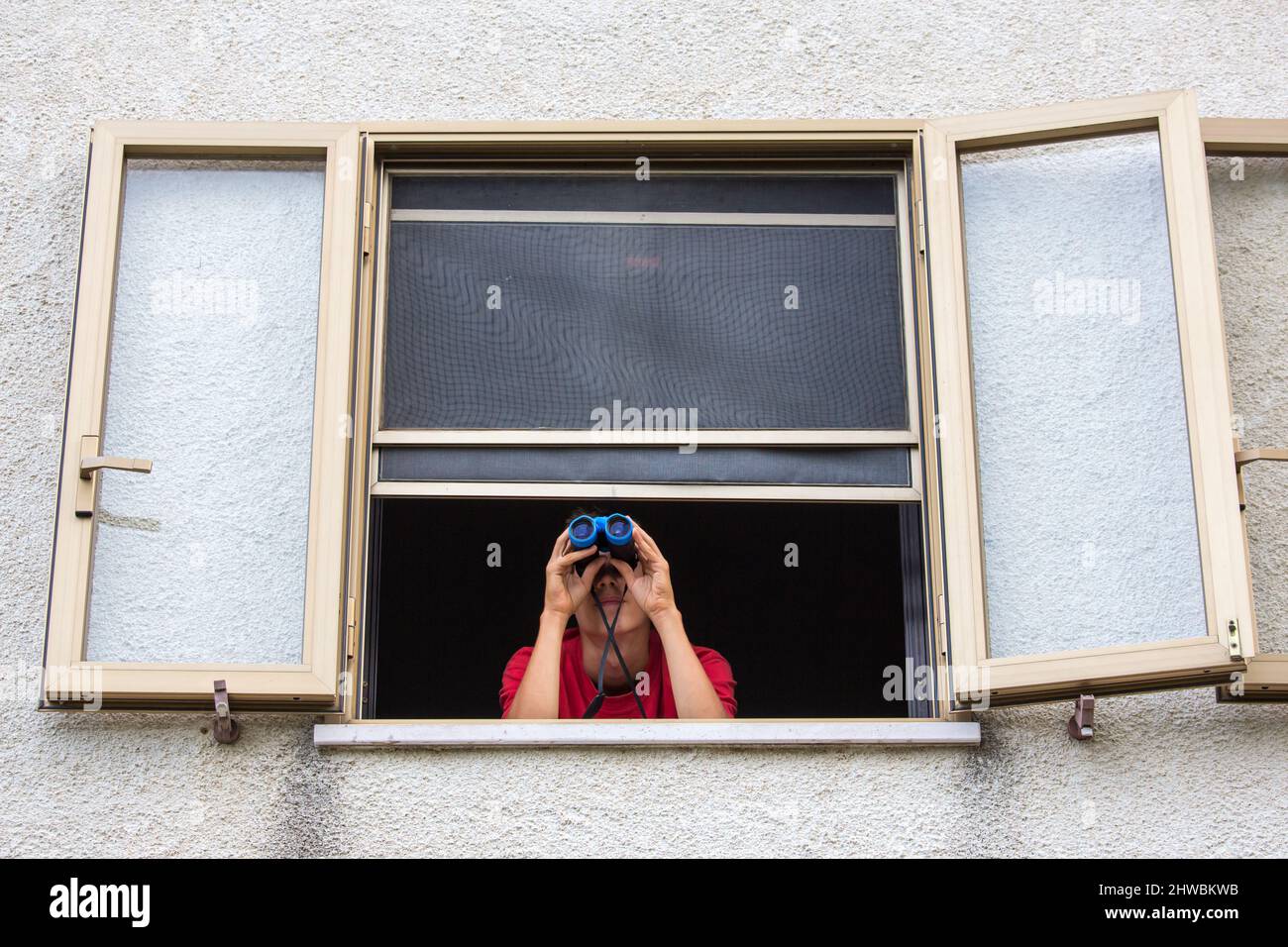 A person with binoculars. A young man investigate or spies on someone ...