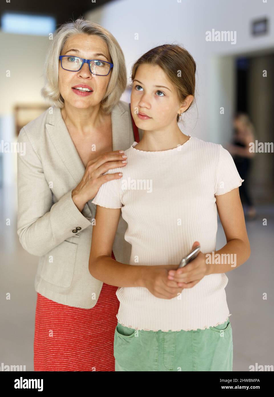 Intelligent female tutor helping tweenage girl exploring art pieces in ...