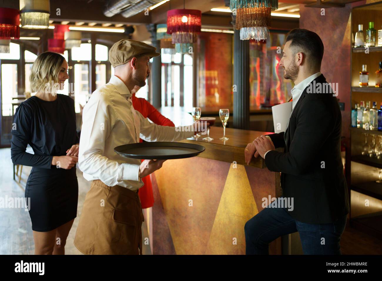 Barman serving cocktail on counter for clients Stock Photo - Alamy