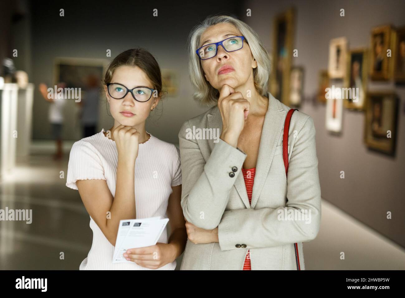 Teenage girl and mature woman observing exhibition in historical museum ...