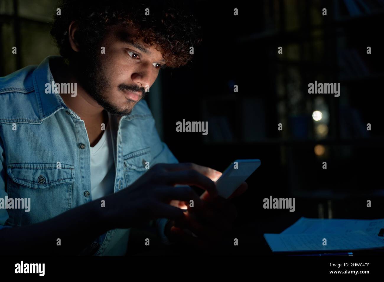 Young indian man using mobile apps on cell phone late at night Stock ...