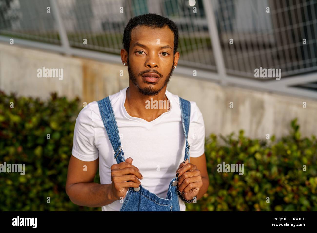 Guy posing in a white shirt and overalls Stock Photo - Alamy