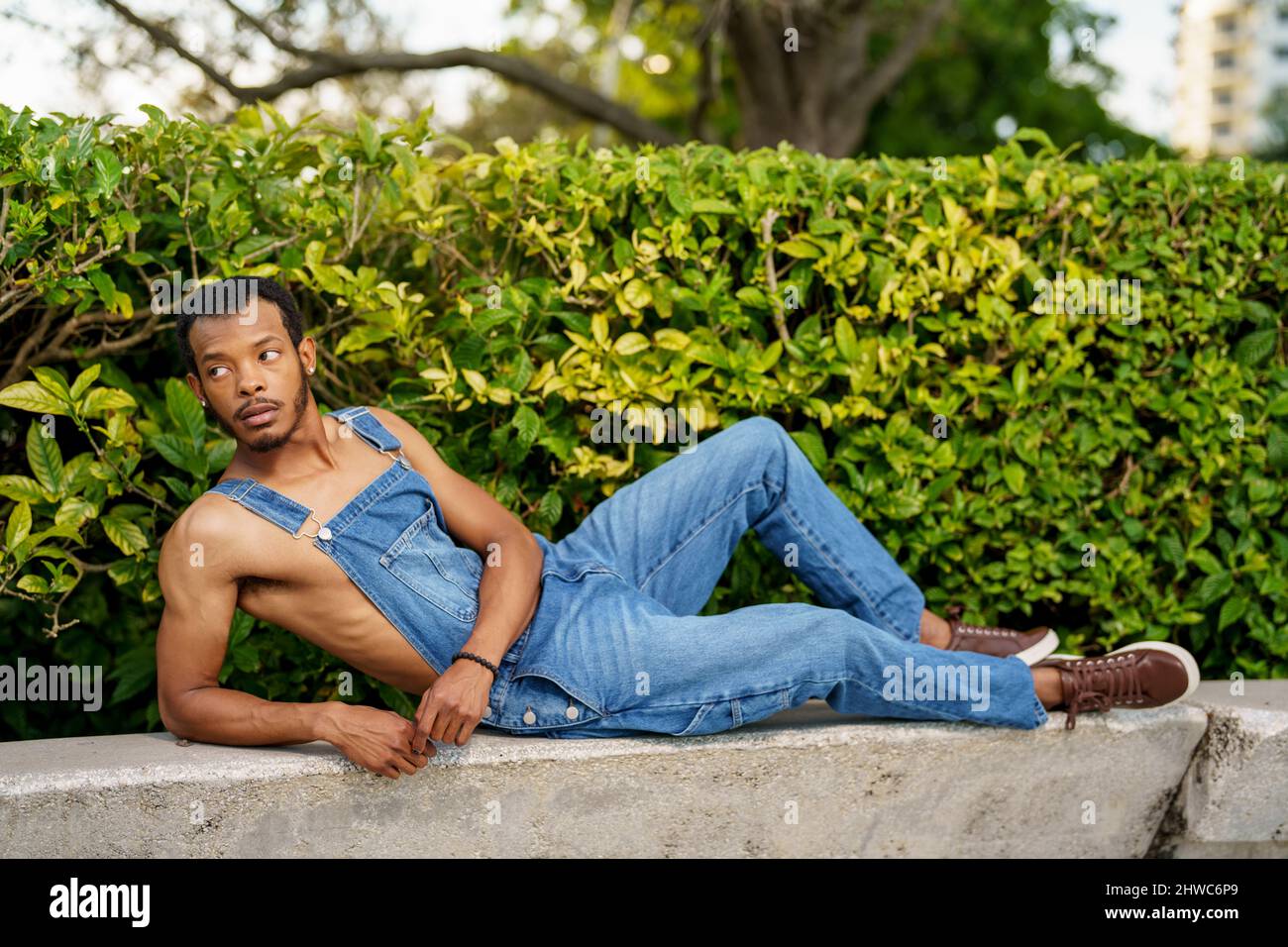 Photo of a man wearing overalls in the park. He is laying down on his ...